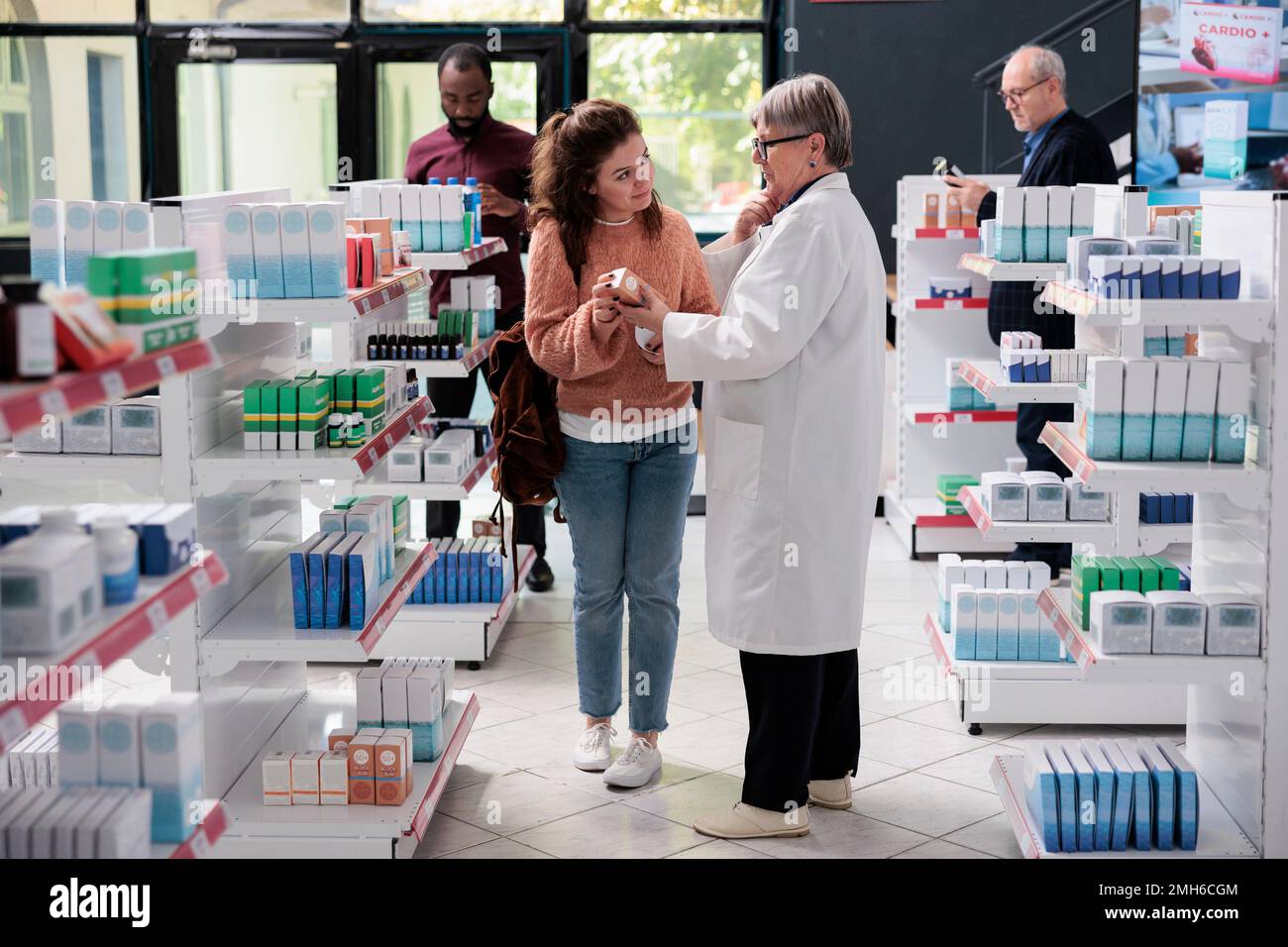 Drugstore senior employee checking box of drugs explaining medical ...