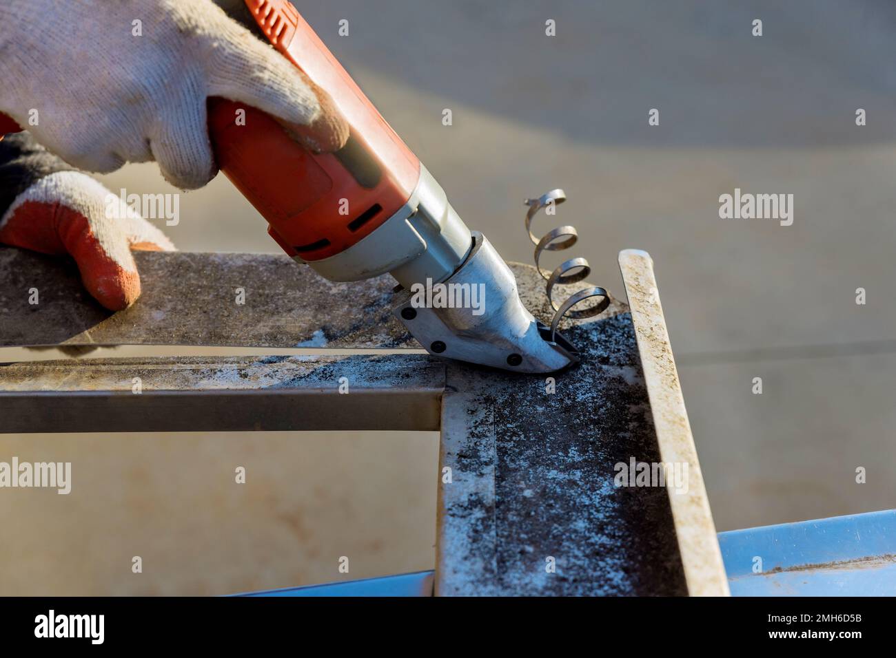 Worker is using electric scissors to cut metal using double shear gauge ...