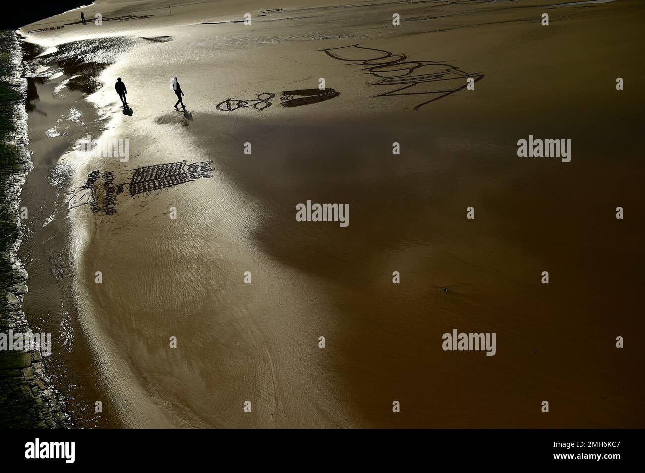 People walk along La Concha beach on a clear winter day in San ...