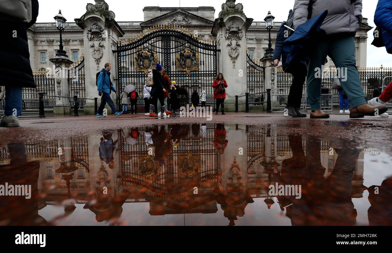 Visitors are reflected in a puddle as they visit Buckingham Palace in ...
