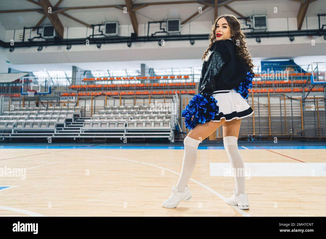 Horizontal shot of cheerleader looking over the shoulder posing with ...
