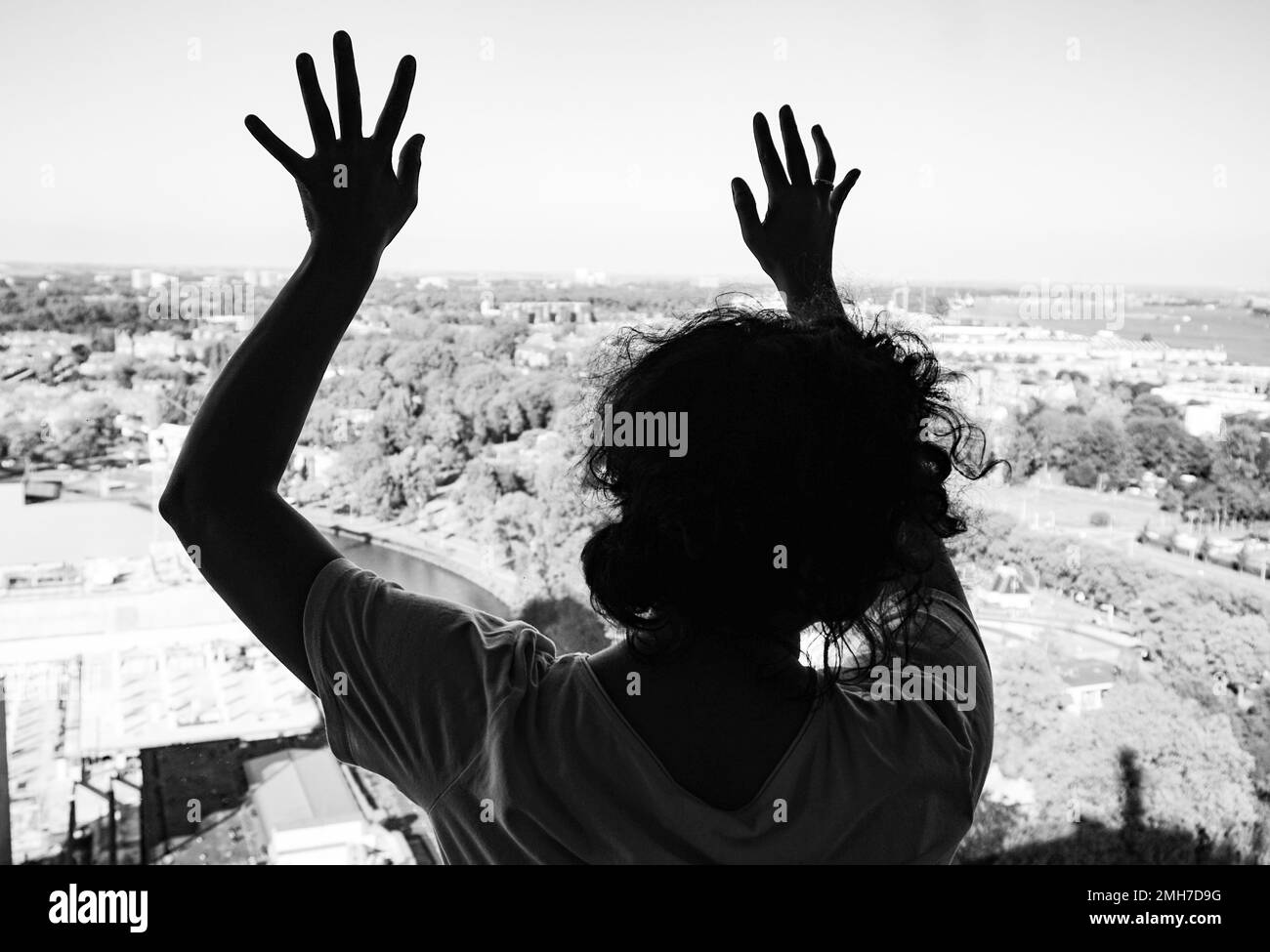 Rear view of woman with arms raised standing against cityscape Stock ...