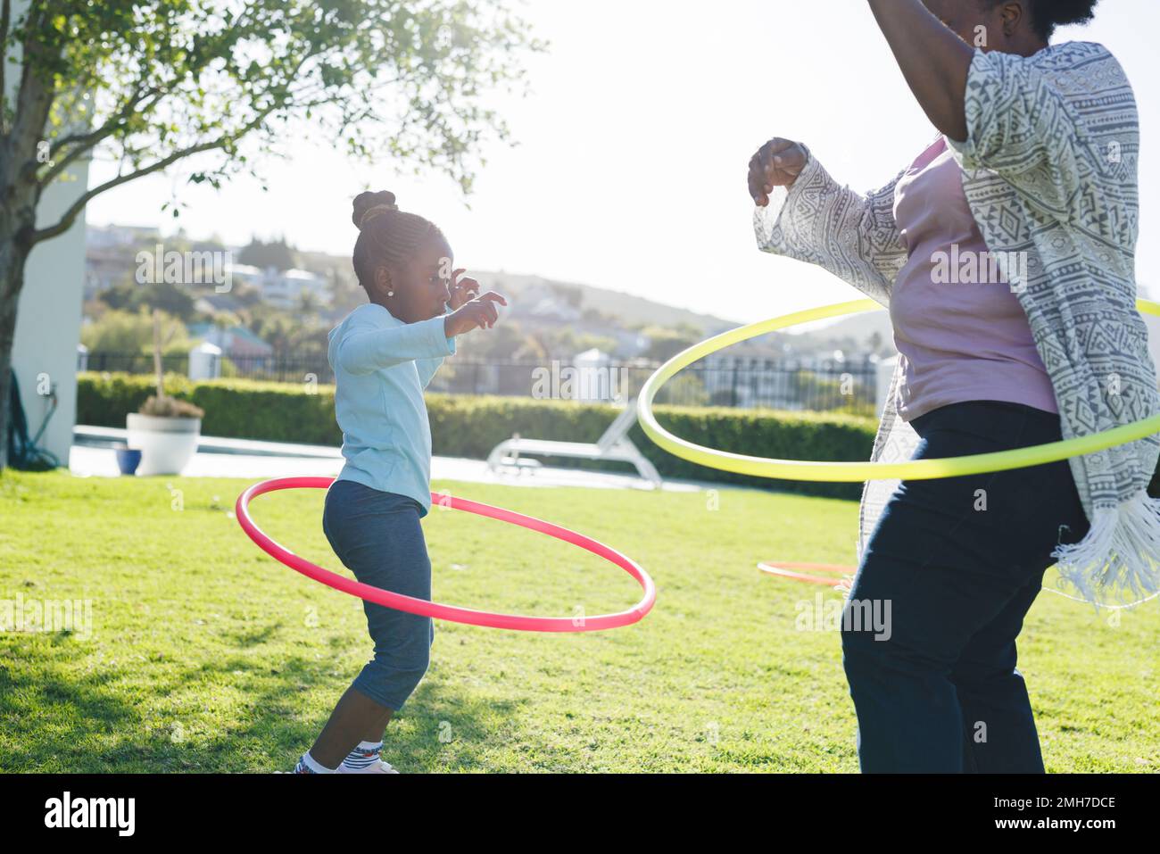 Happy african american grandmother and granddaughter using hula hoop in ...