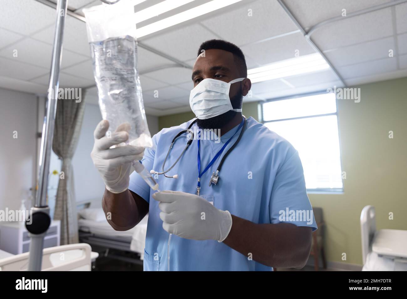 African american male doctor wearing face mask, working at hospital ...