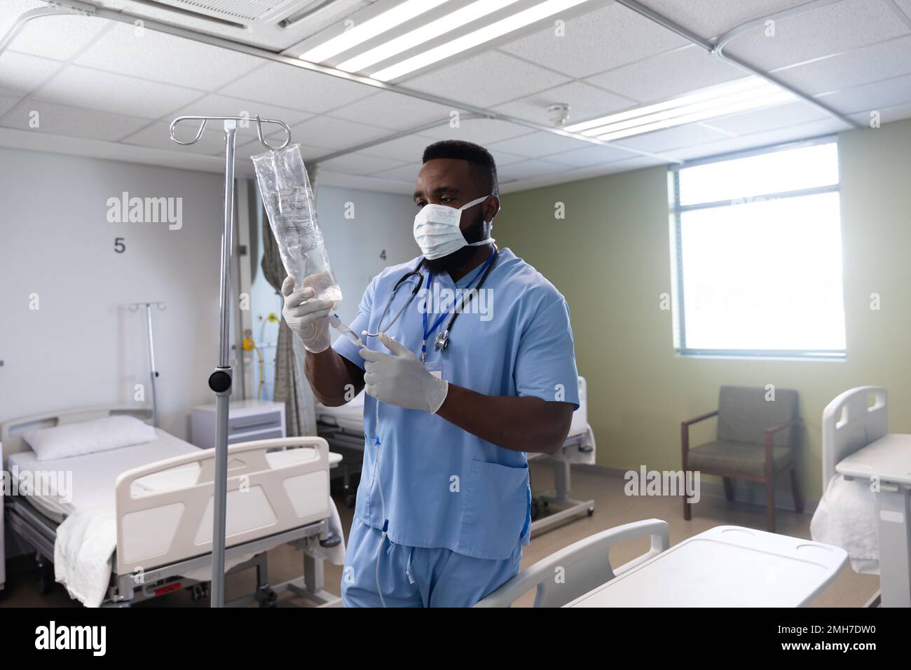 African american male doctor wearing face mask, working at hospital ...