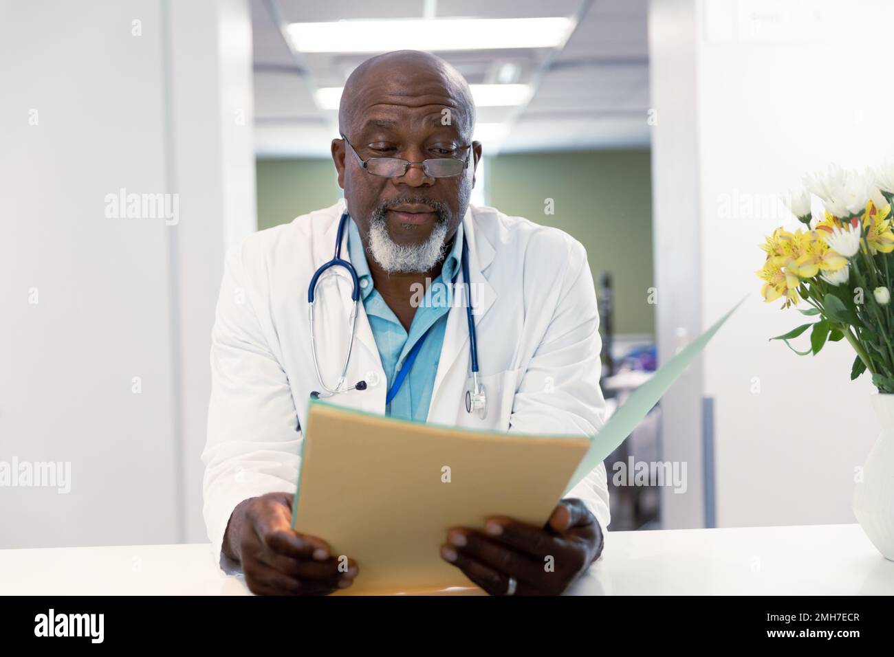 African american male doctor working at hospital, reading documents ...