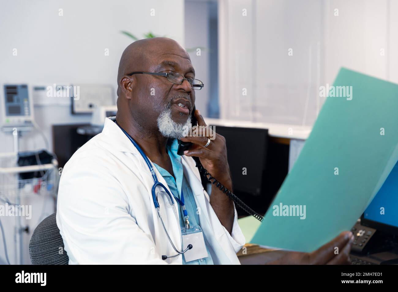 African american male doctor working at hospital, talking on telephone ...
