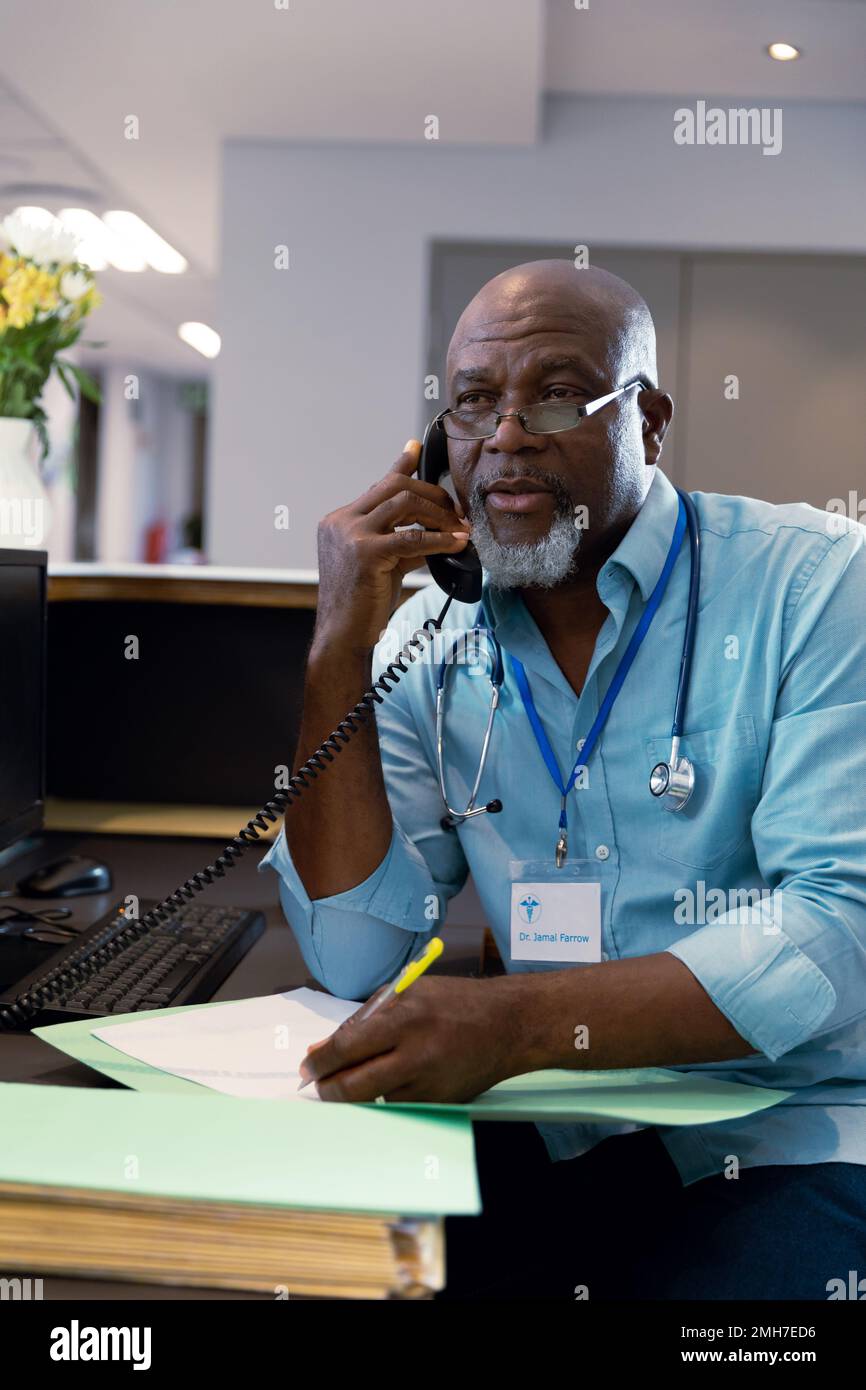 African american male doctor working at hospital, talking on telephone ...