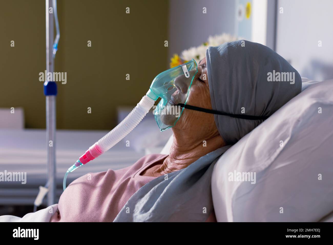 Senior caucasian female cancer patient wearing head scarf in bed with ...