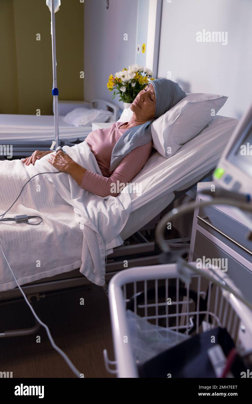 Senior caucasian female cancer patient wearing head scarf lying in bed ...