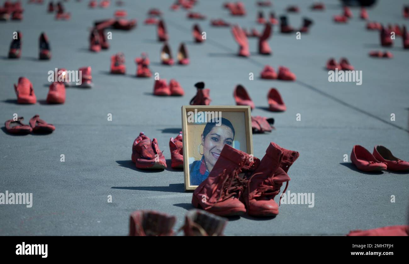 A portrait of Eugenia Machuca Campos sits amid women's red shoes placed ...