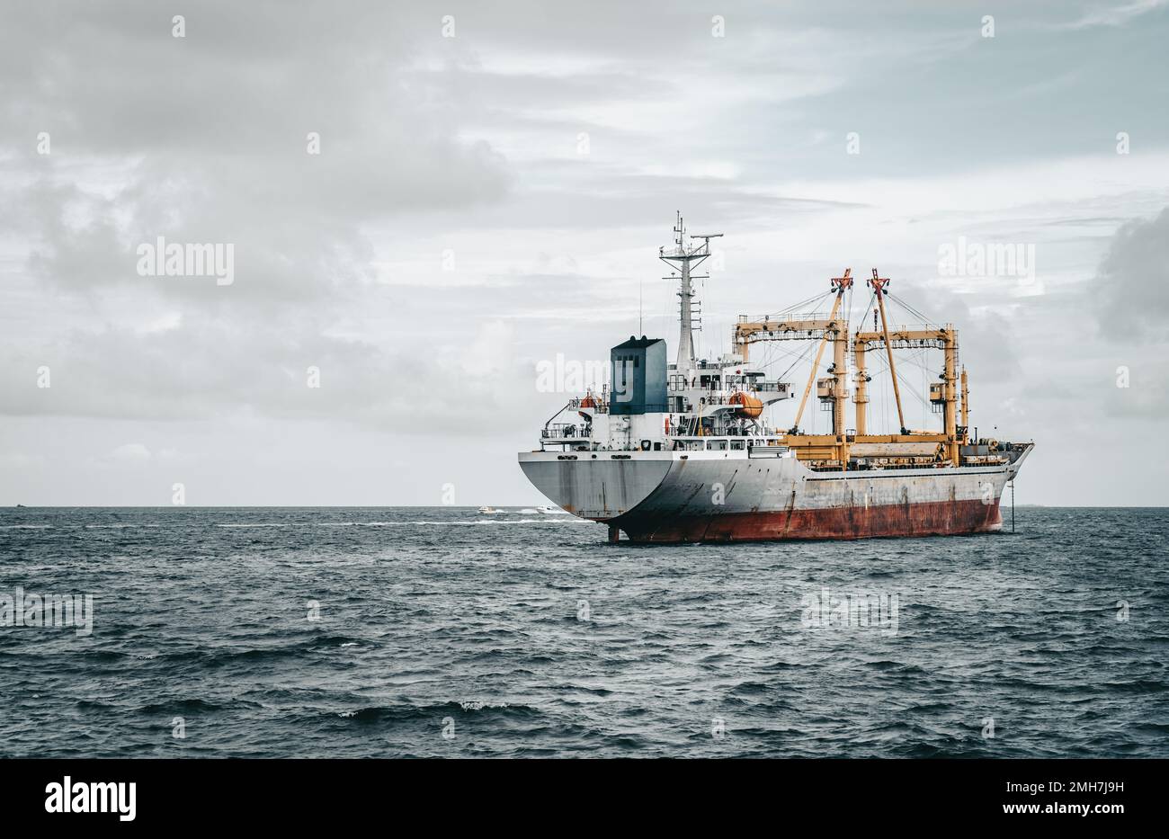 View from behind of a huge freighter in the ocean with two cargo cranes ...