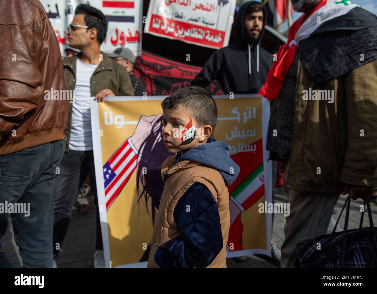A child with the colors of the Iraqi flag on his face walks past a ...