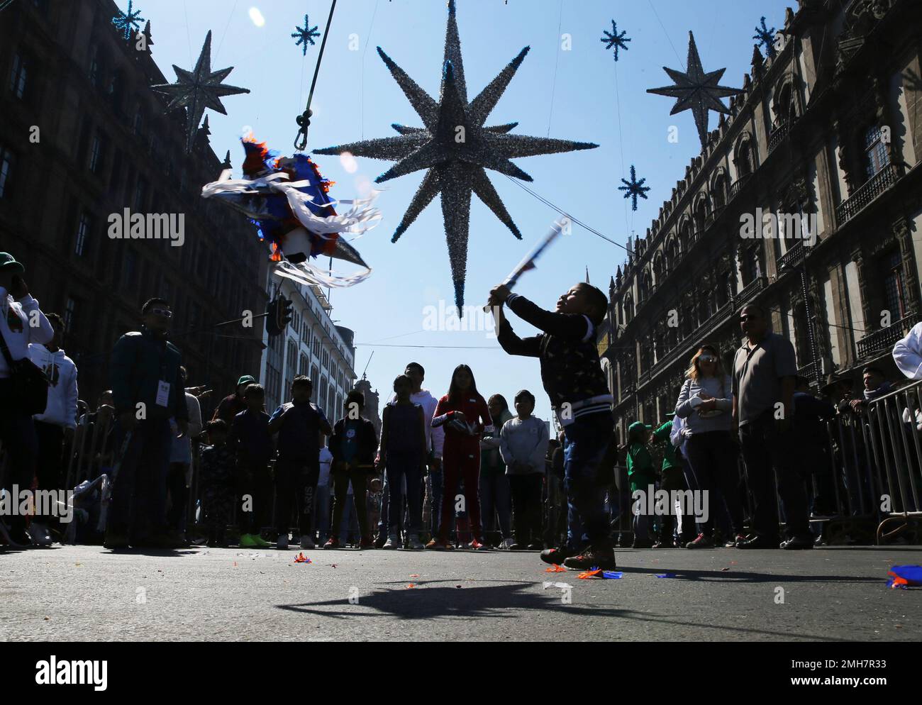 A girl hits a traditional Christmas "piñata" filled with fruit and ...