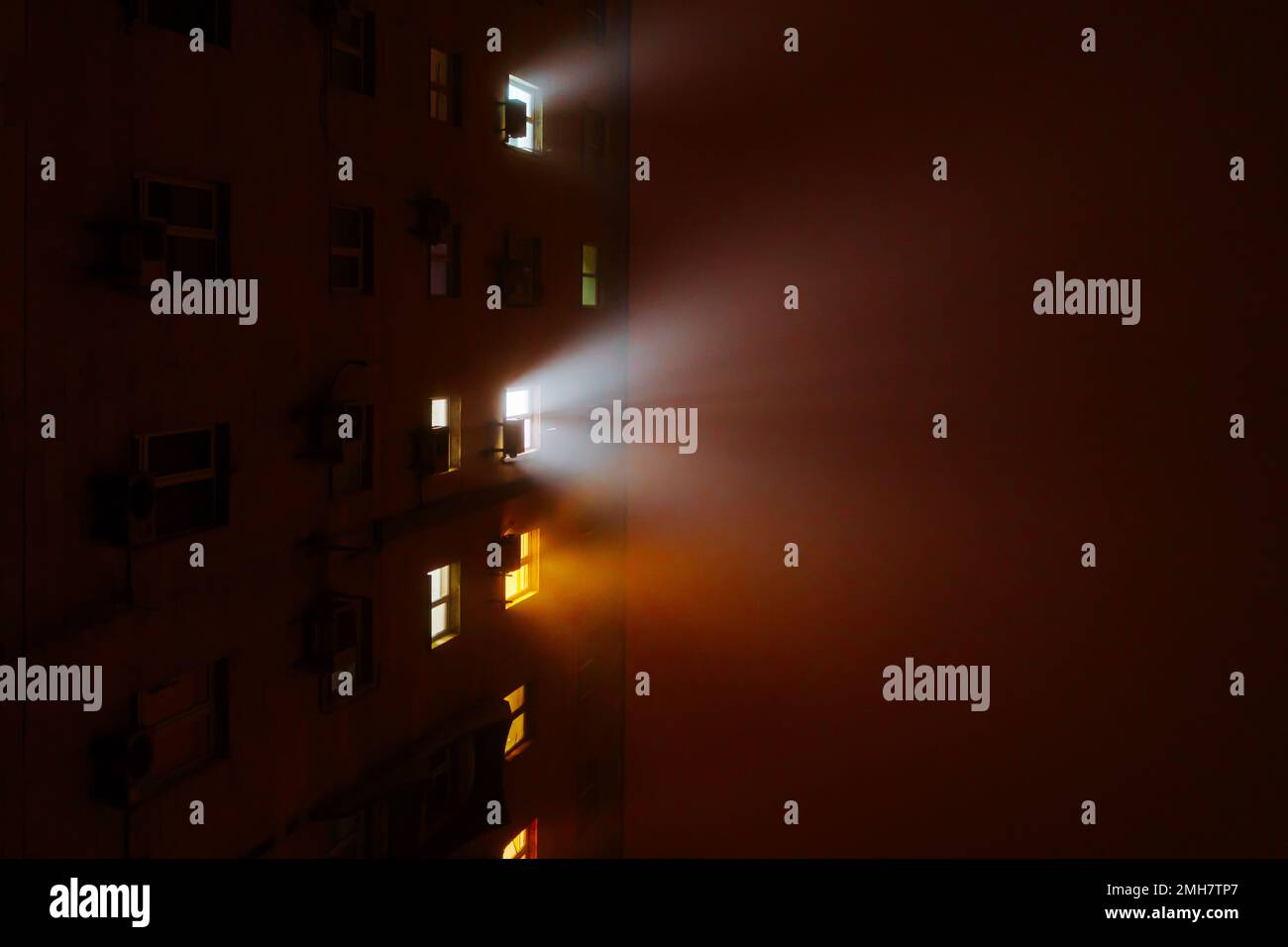 Mystical light from the windows of the house. Rays pass through the fog ...