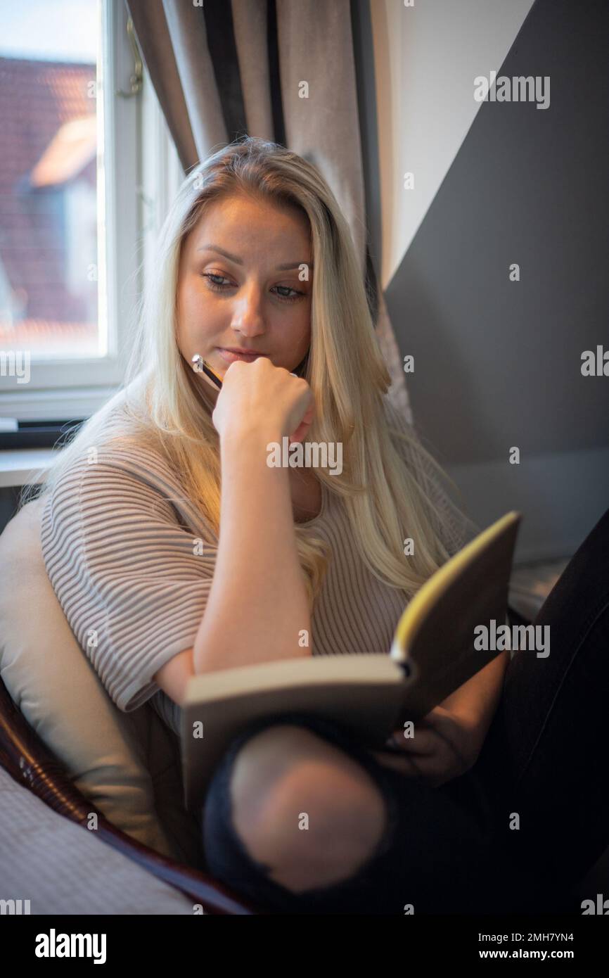 A thoughtful young woman writes in her diary while sitting on the ...