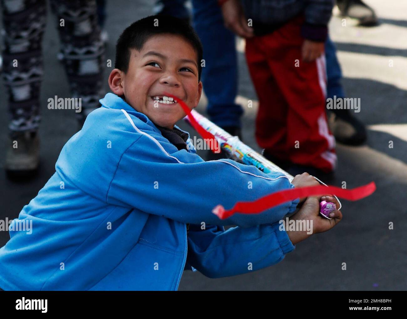 A boy hits a traditional Christmas “pinata” filled with fruit and candy ...
