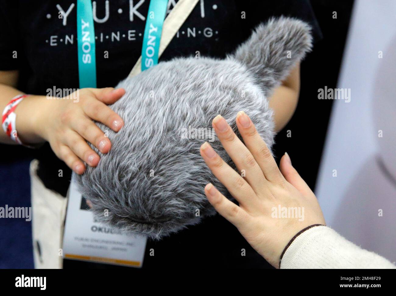People pet the Qoobo tailed cushion at the Yukai Engineering booth ...