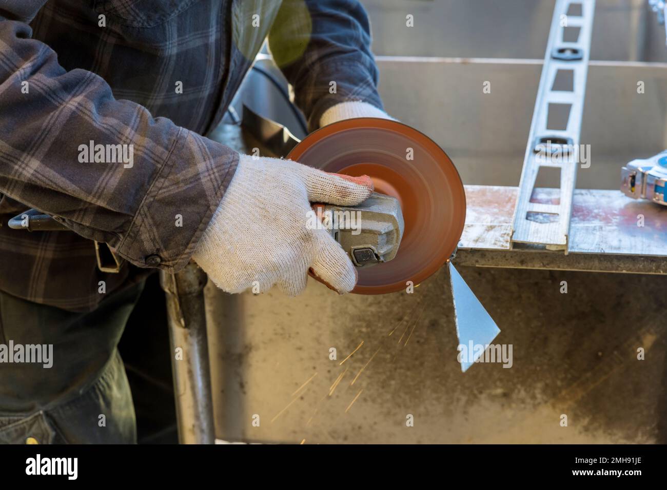 Worker uses grinder to cut metal with sparks while grinding iron with ...