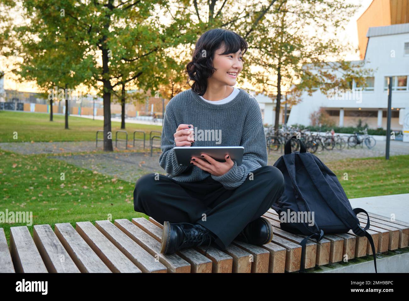 Young asian girl, student sits on bench, graphic designer with pencil ...