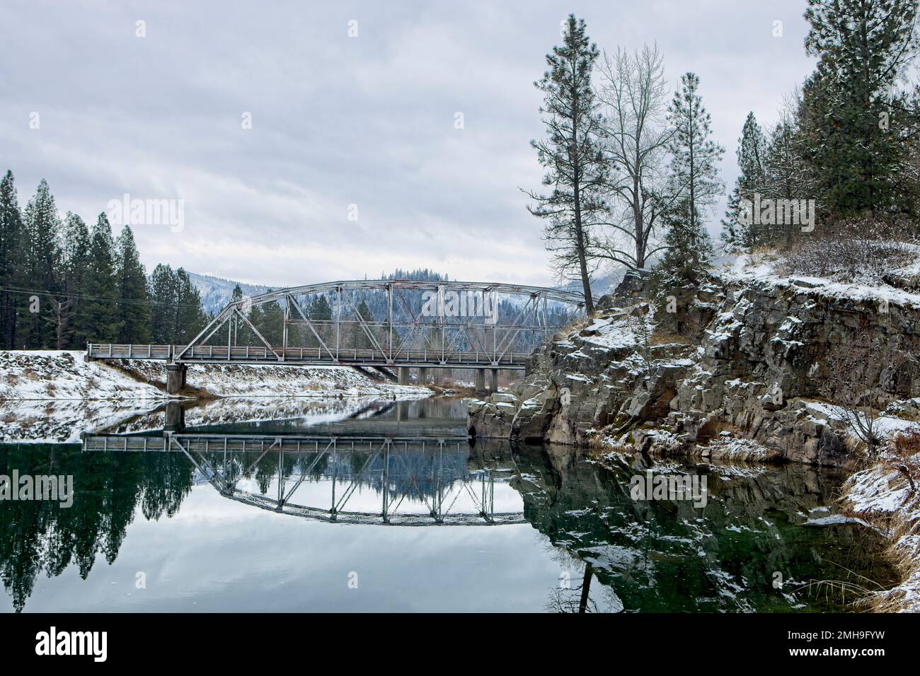 An older steel bridge spans across the calm Coeur d:Alene River in ...