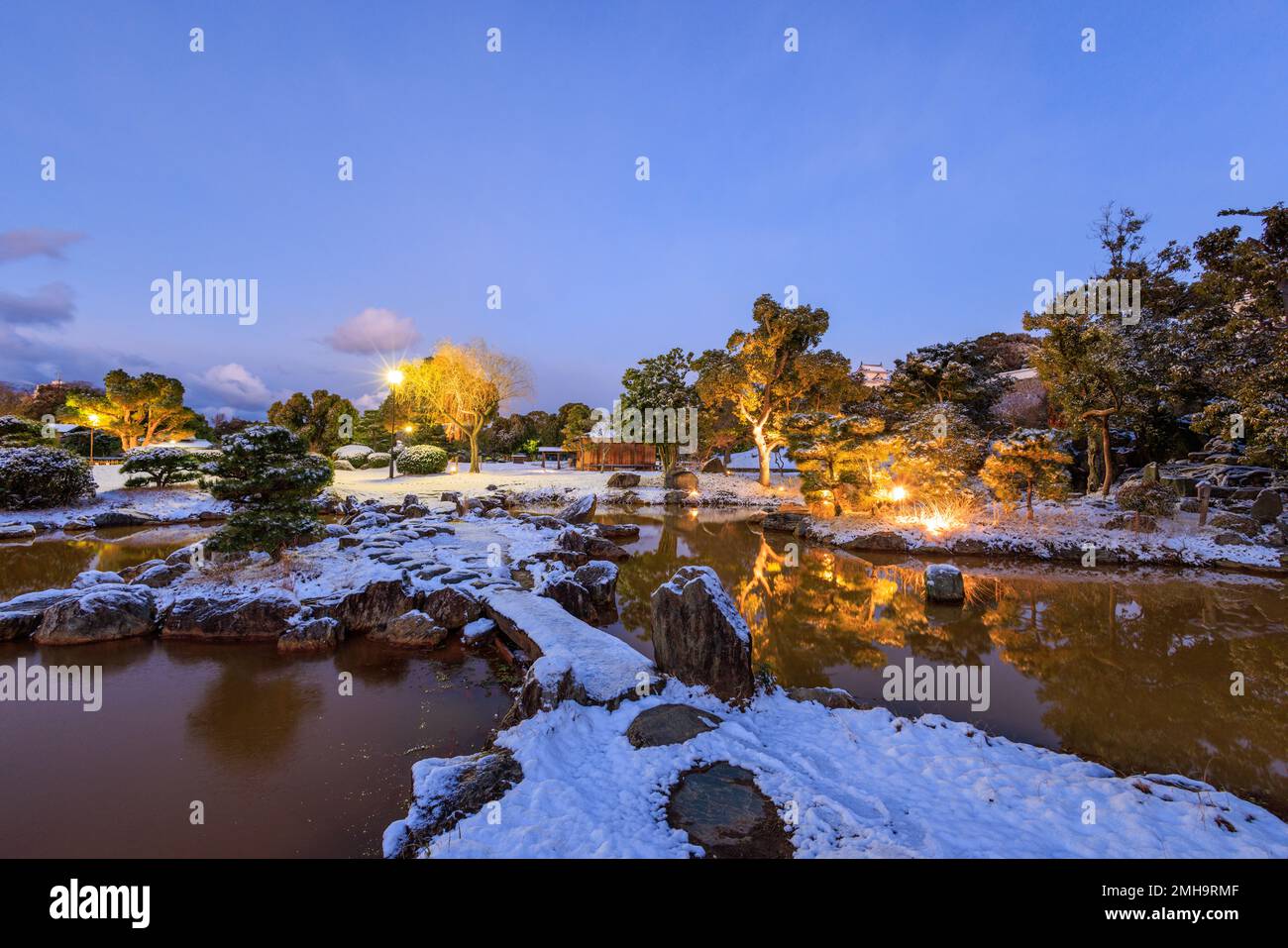 Snow covered stone bridge over pond in Japanese garden at dawn Stock ...