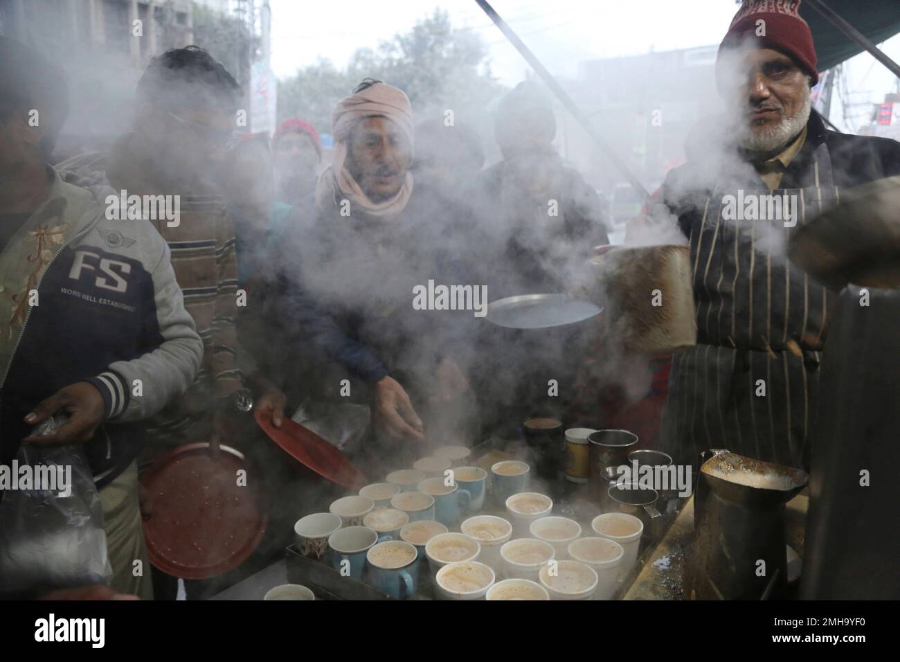 Pakistani customers wait for a cup of tea at a stall to keep themselves ...