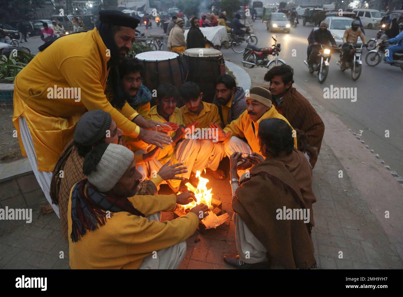 Pakistani street performers sit around a fire to keep themselves warm ...