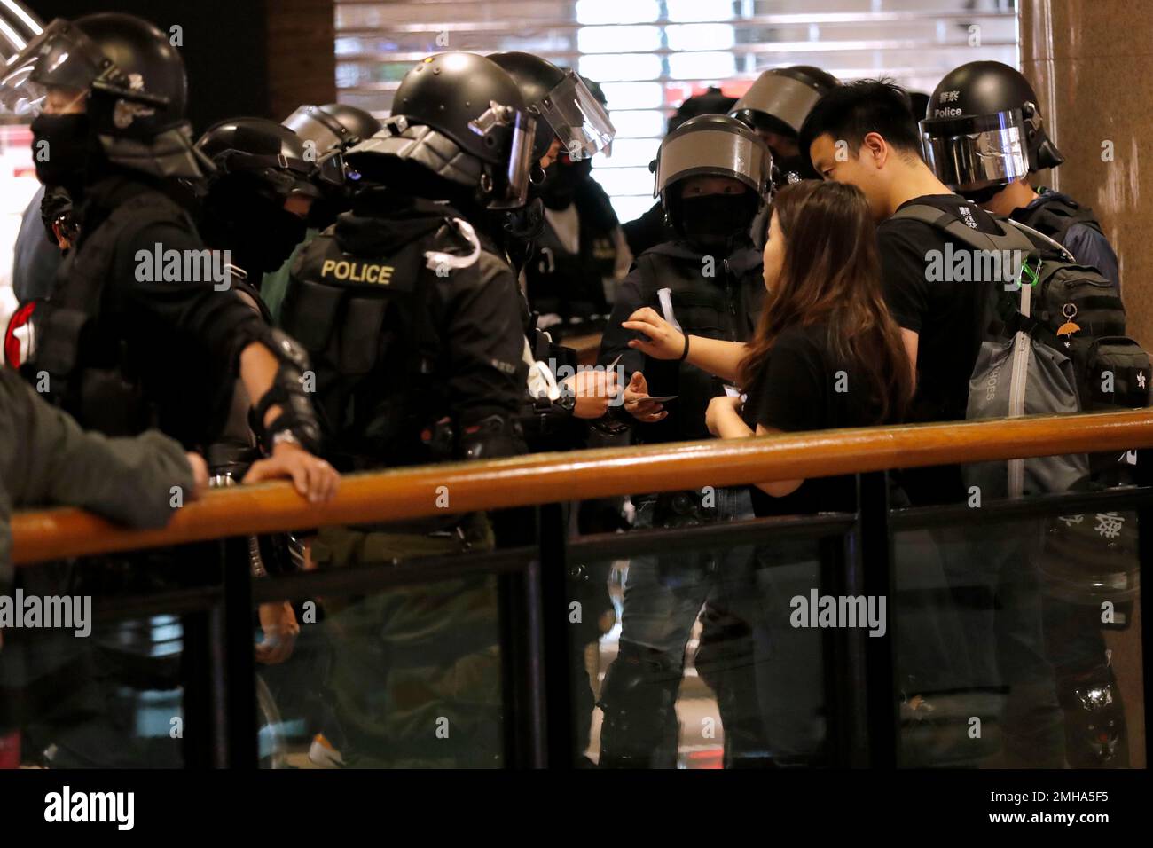 Riot police check the identification of people in a shopping mall as ...