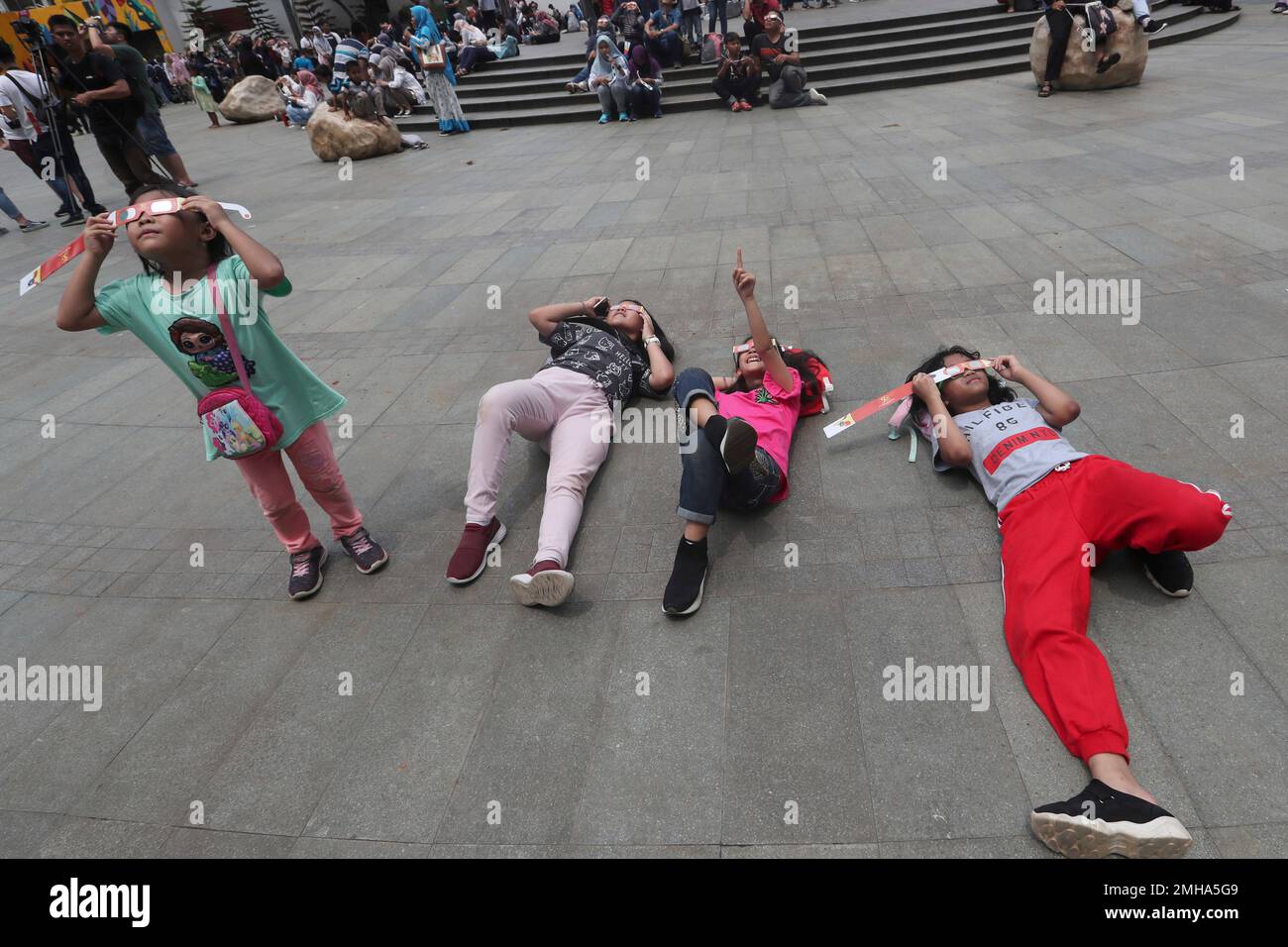 People look up at the sun wearing protective glasses to watch a solar ...