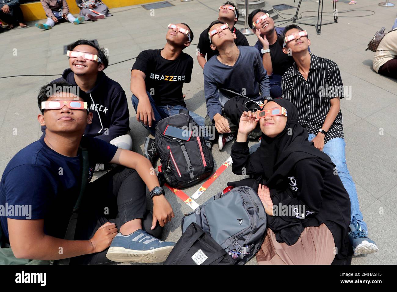 People look up at the sun wearing protective glasses to watch a solar ...