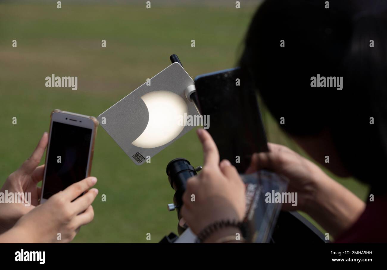 Students take a picture of a reflection of a partial solar eclipse at a school in Bangkok ...