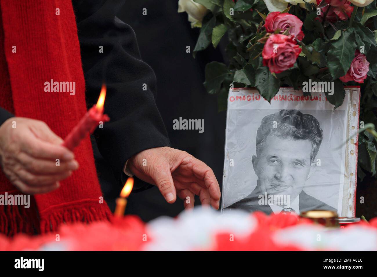 A man lights candles next to a portrait of Romanian communist dictator ...