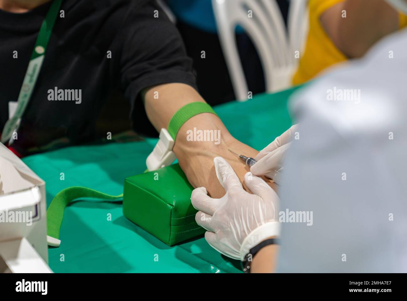A nurse is using a needle to pierce a vein in his arm for examination ...