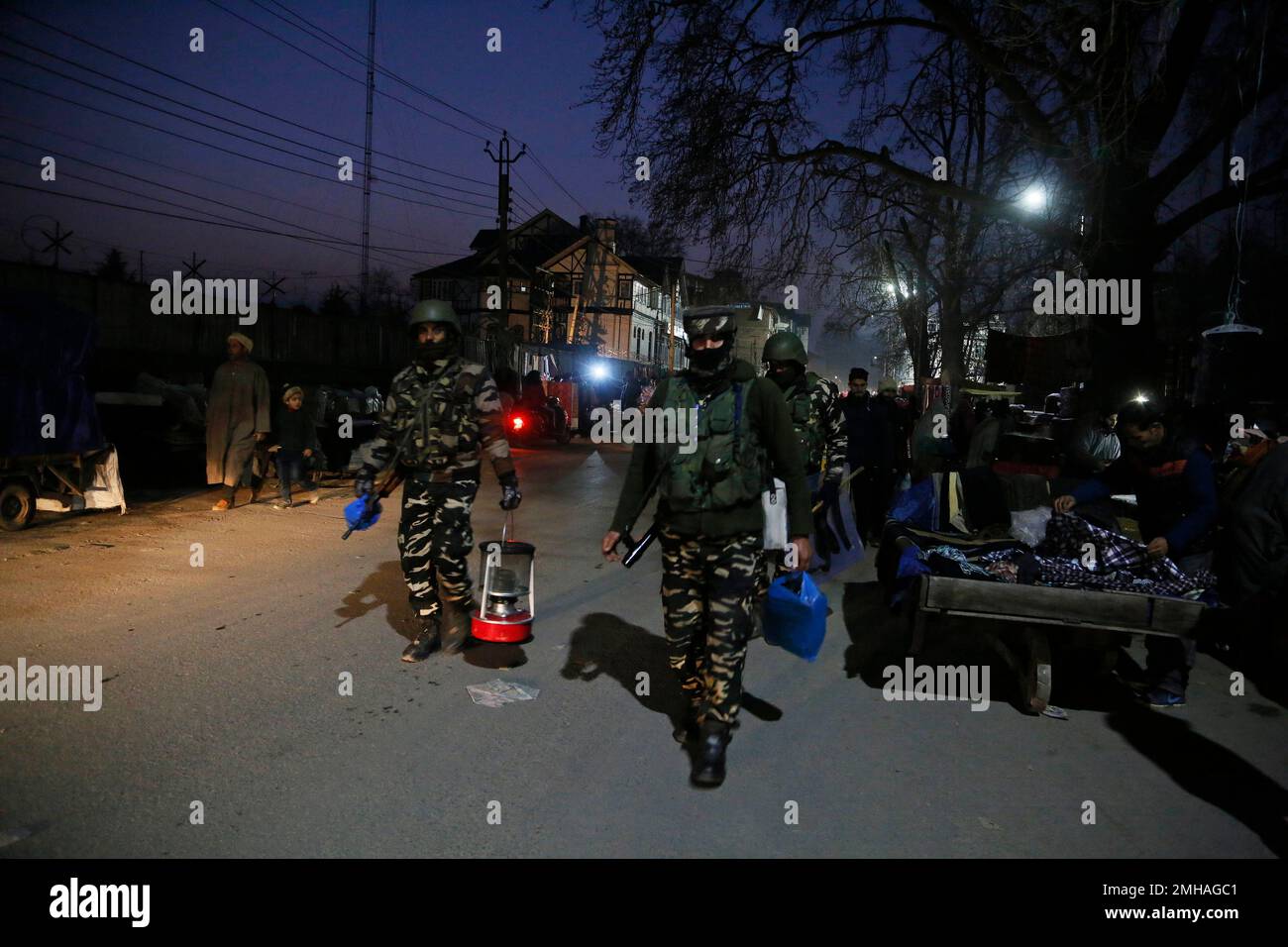 An Indian paramilitary soldier walks carrying a heater as they return ...