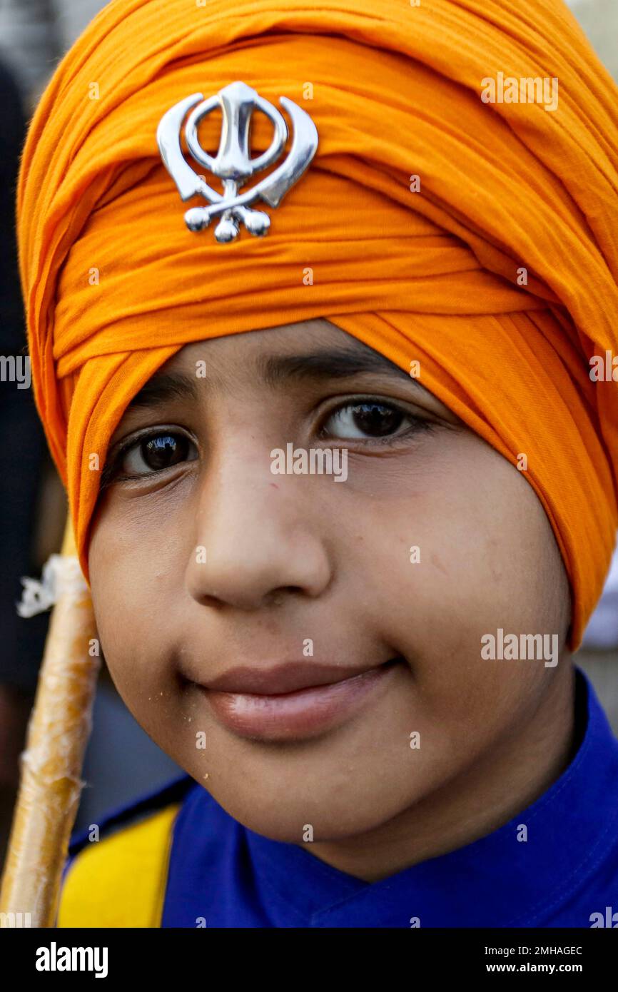 A Sikh boy in a traditional attire has religious symbols on his ...
