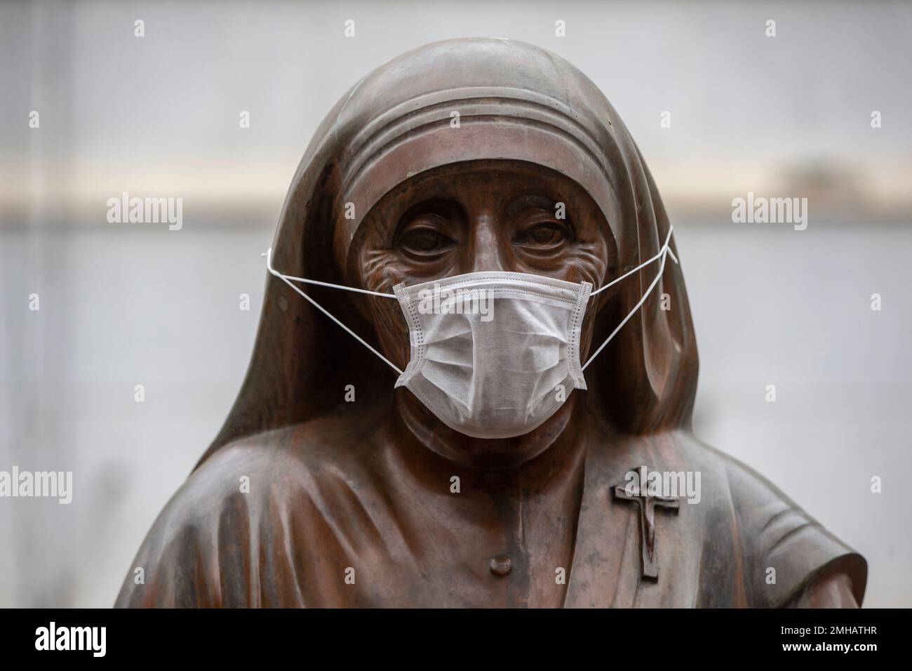 A mask covers the mouth and nose of the St. Mother Theresa with a child ...