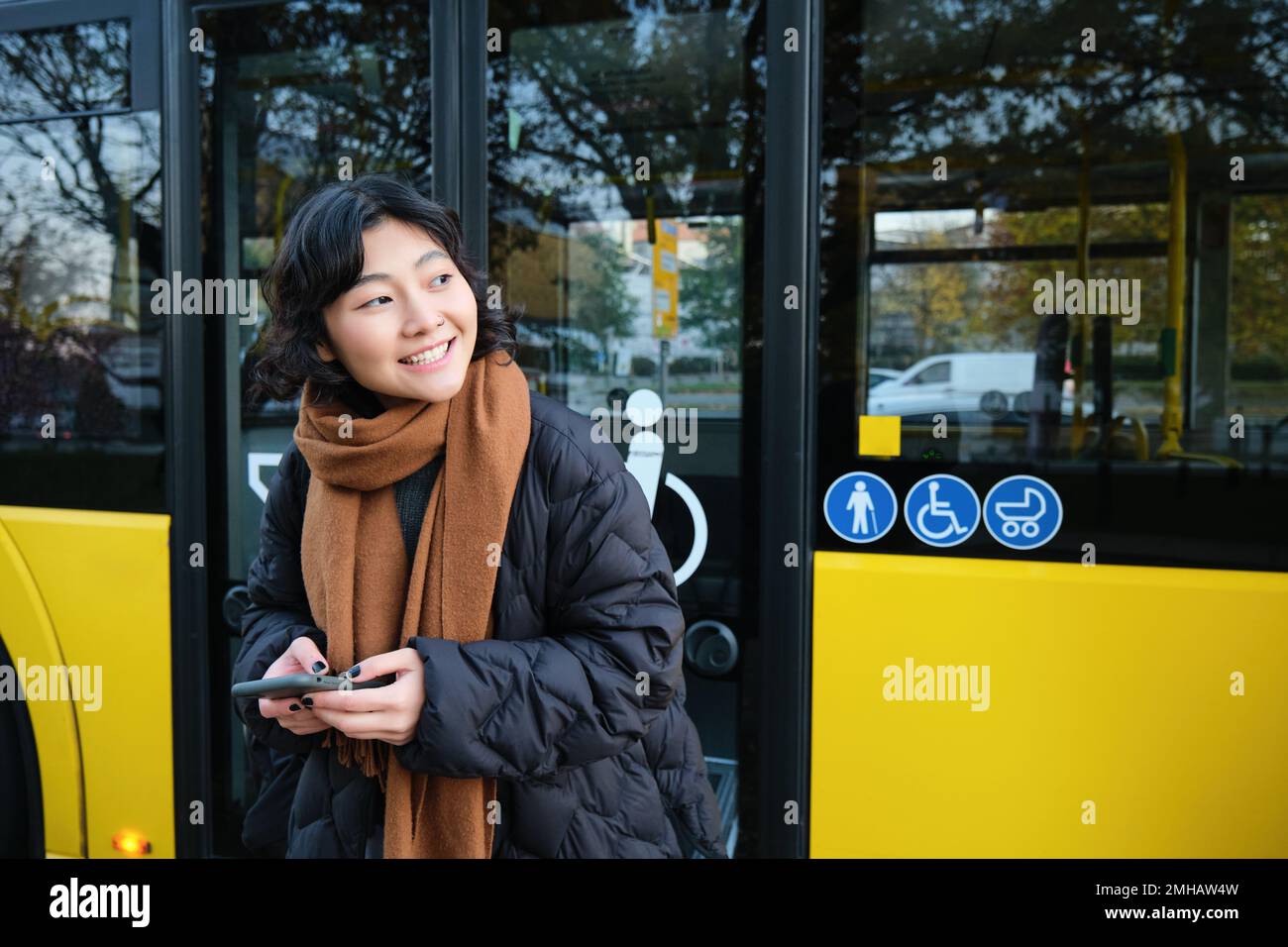 Portrait of korean girl looking for her bus on a stop, holding mobile ...