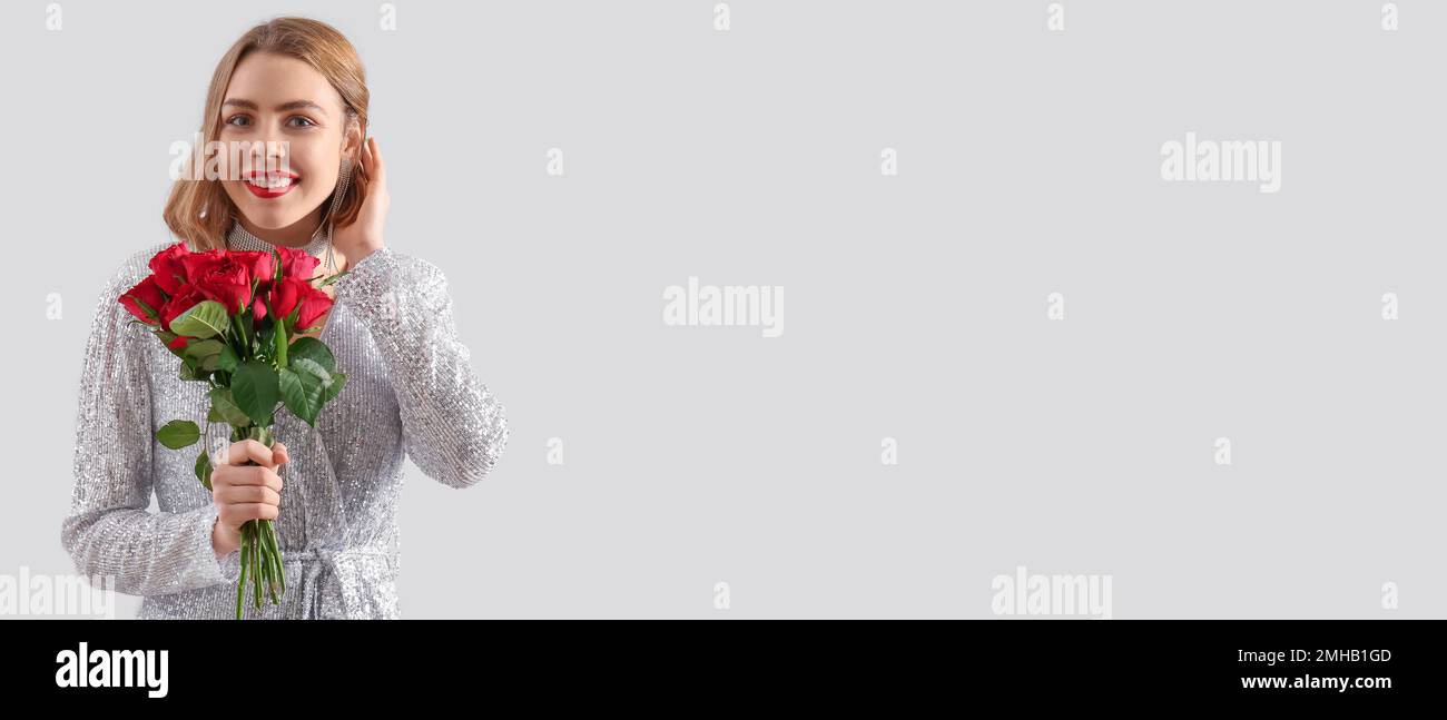 Beautiful young woman with bouquet of red roses on light background ...