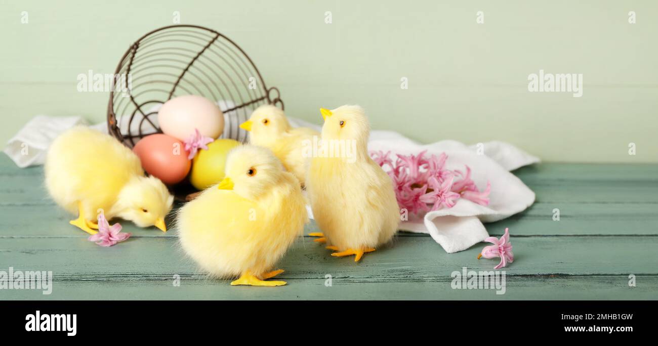 Cute chickens, overturned basket with Easter eggs and flowers on wooden ...