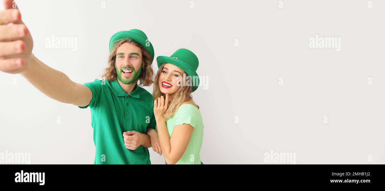 Young couple taking selfie on light background with space for text. St ...