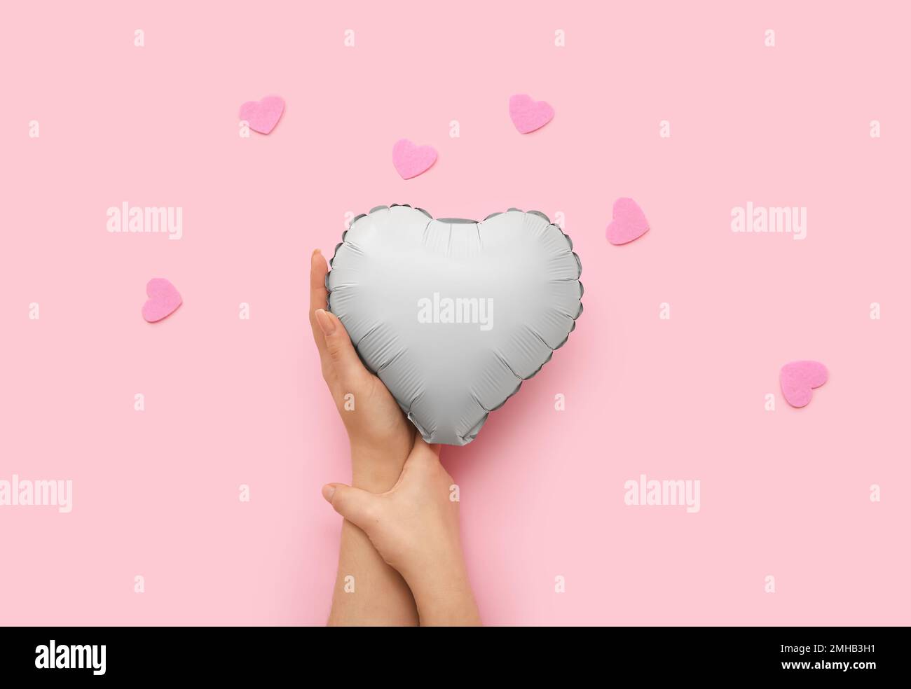 Female hand with heart shape balloon and decor on pink background ...