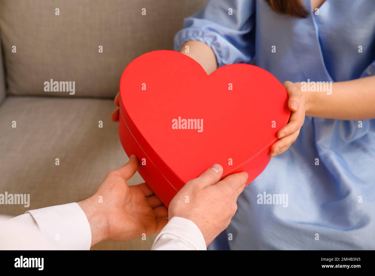 Woman receiving heart-shaped gift from her boyfriend at home. Valentine ...