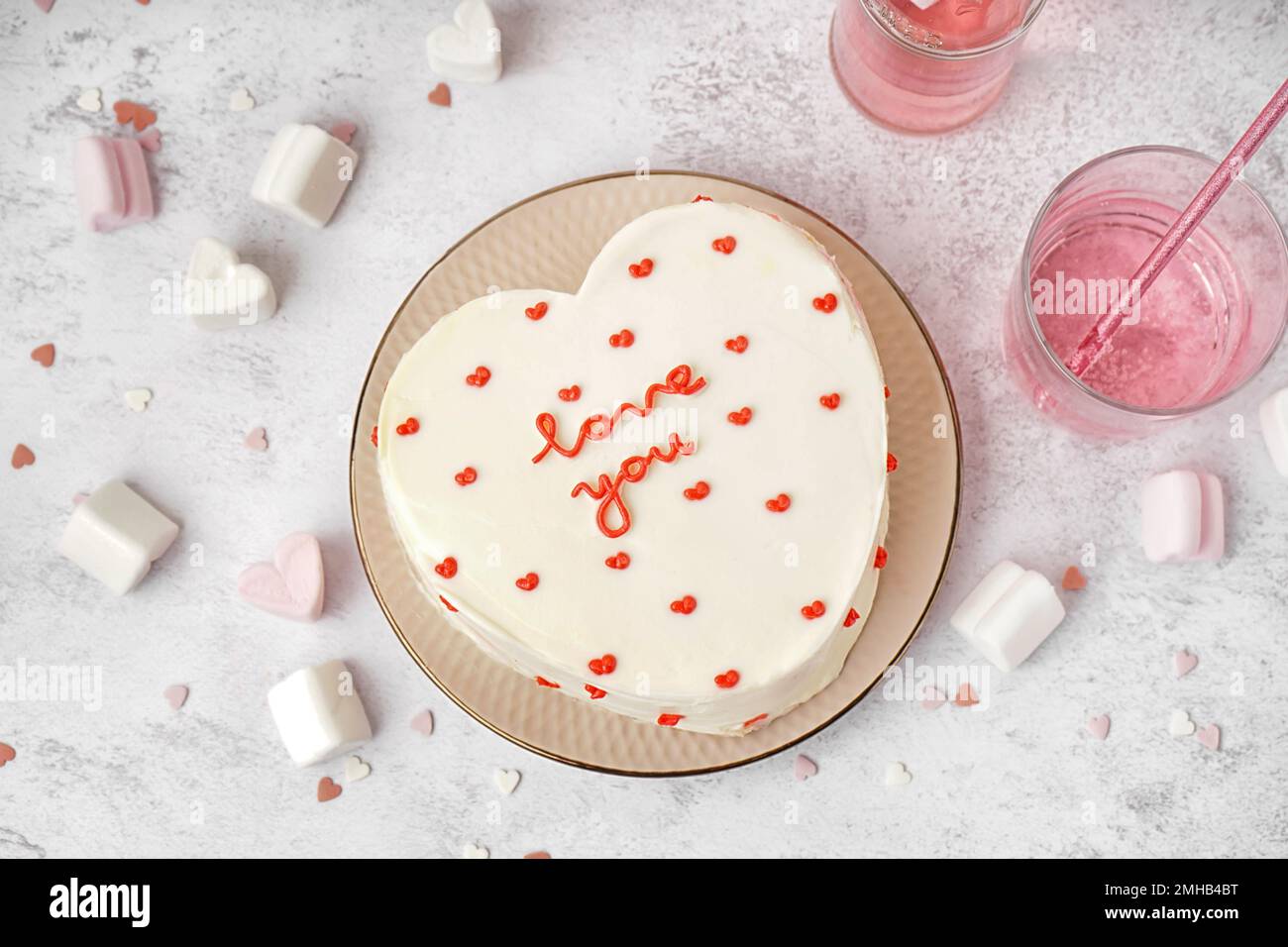 Plate with heart-shaped bento cake and glass of tasty drink on grey ...
