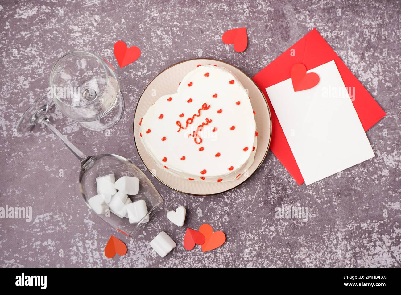 Plate with heart-shaped bento cake and envelope on grey background ...