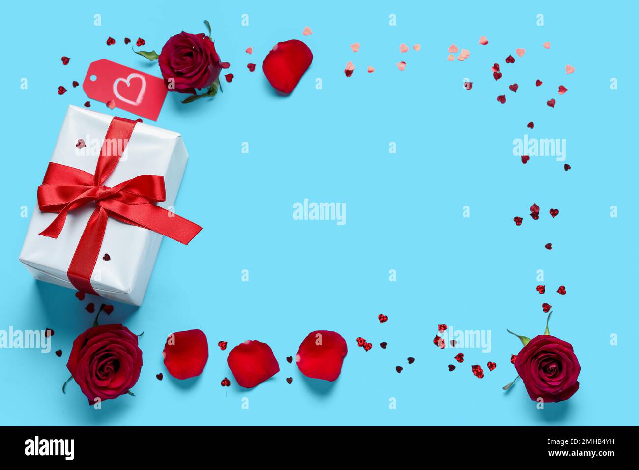 Frame made of gift box, rose flowers and petals on blue background ...