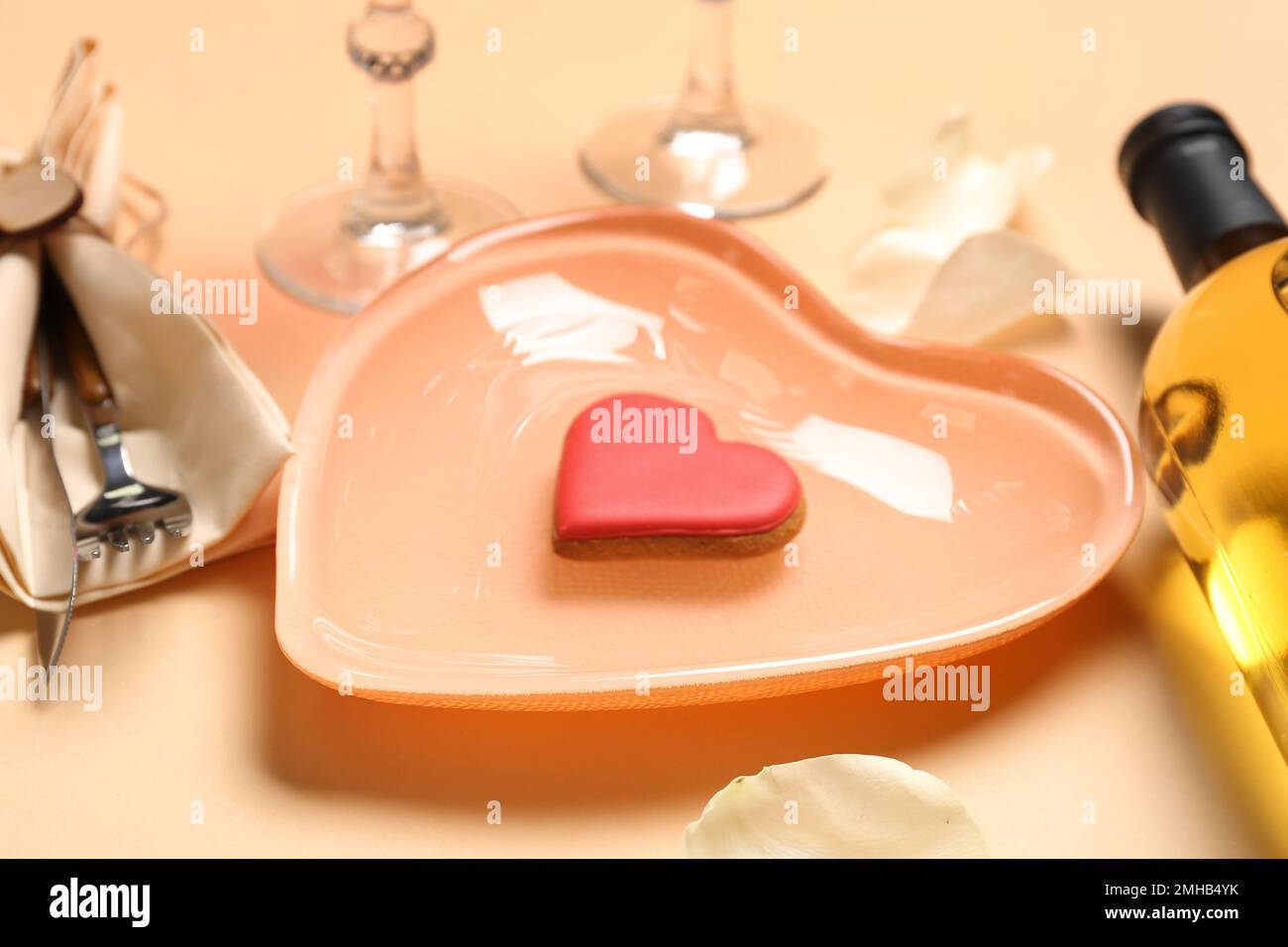 Heart shaped plate with cookie, bottle of wine and cutlery on color ...