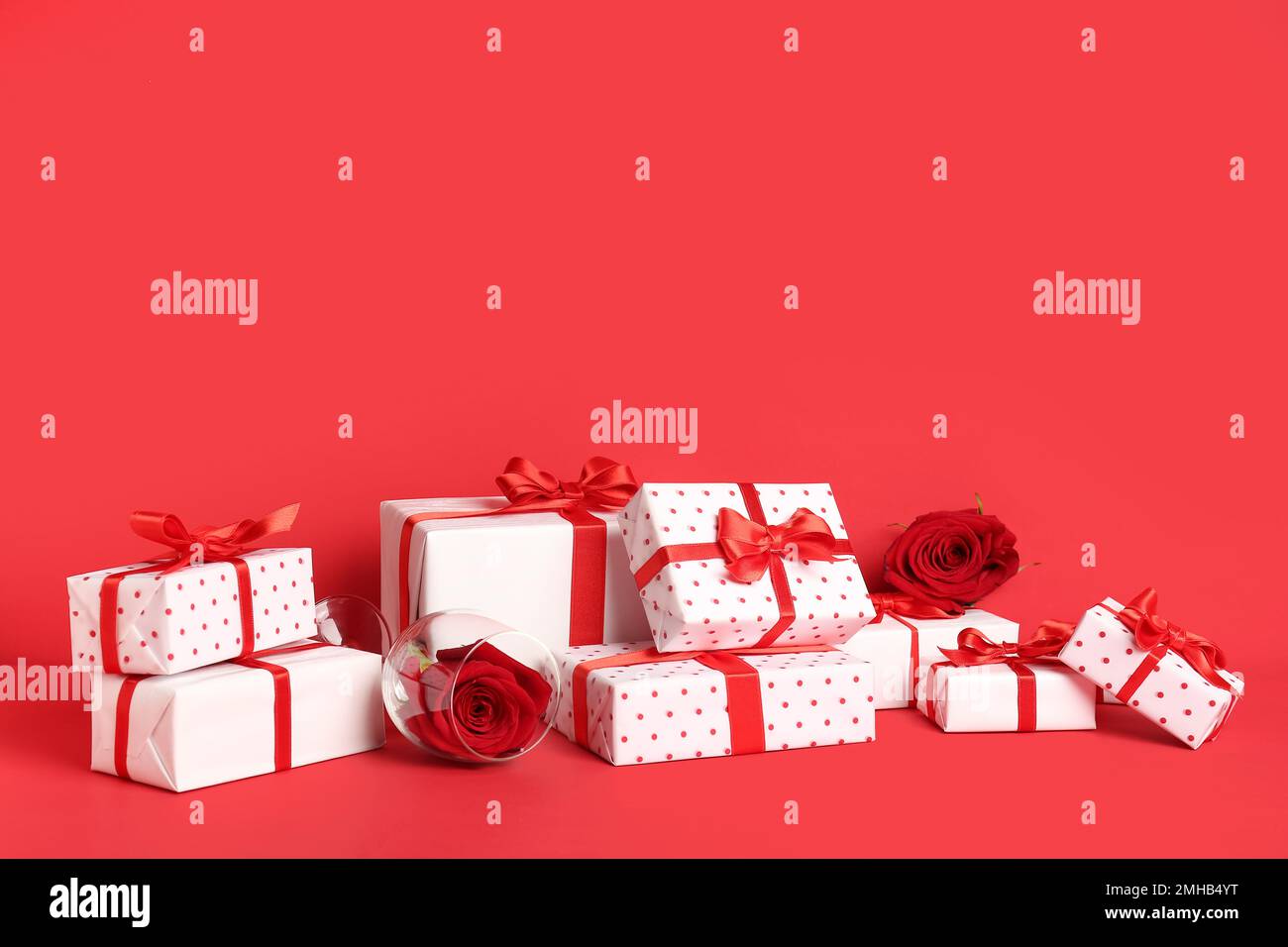 Gift boxes with beautiful bows and rose flowers on red background ...