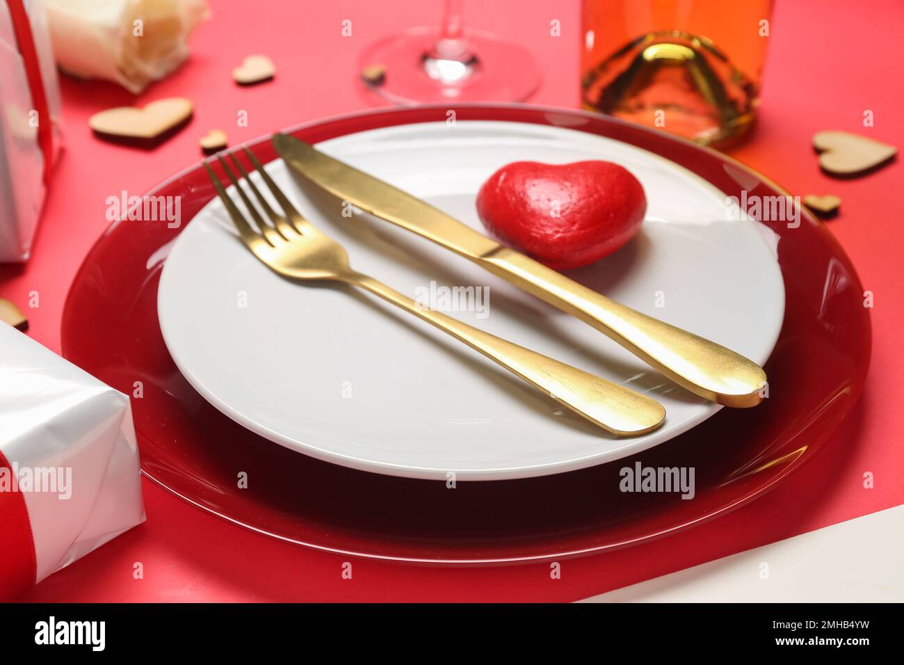 Plate with heart figure and golden cutlery on red background. Valentine ...