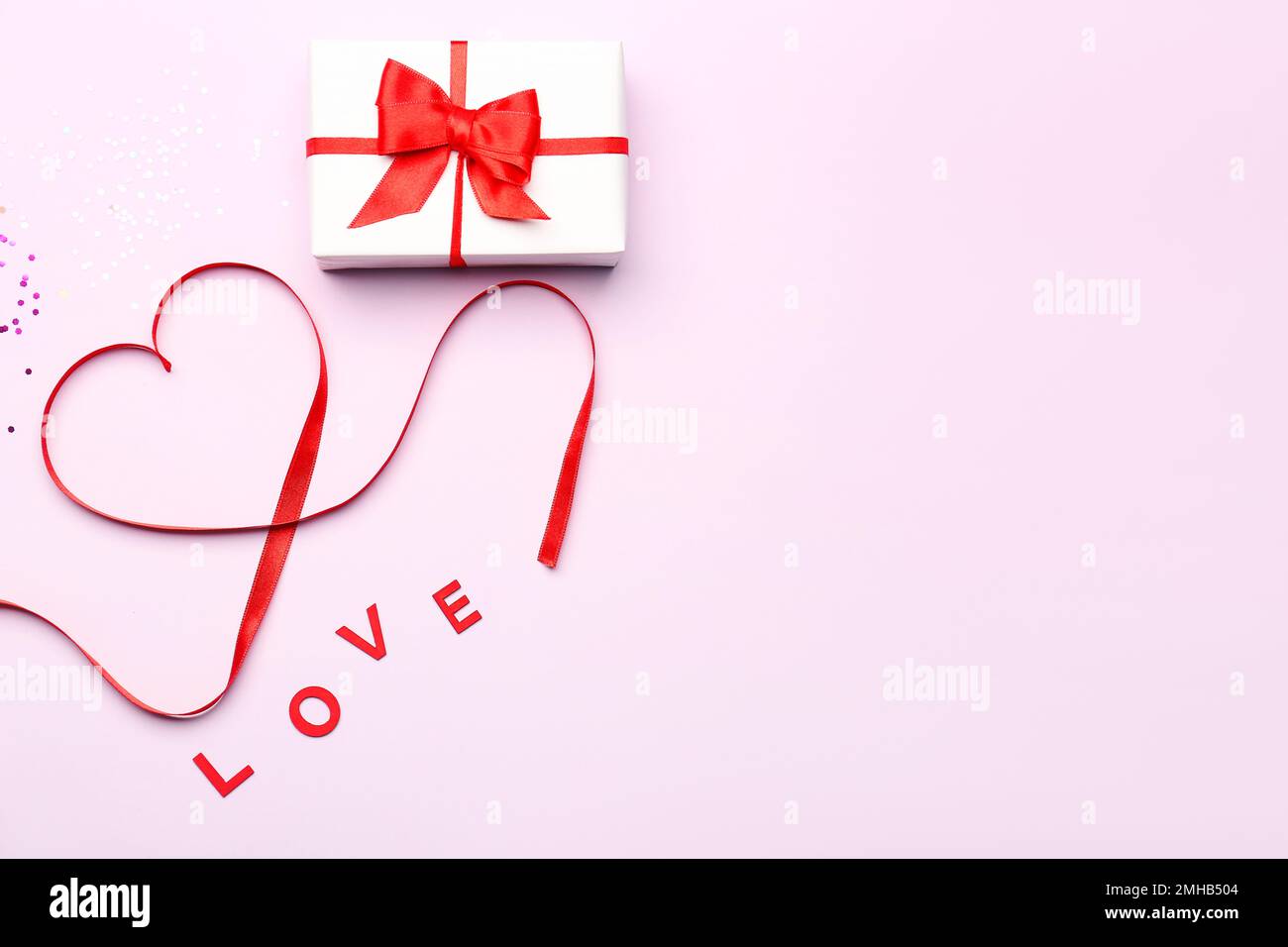 Word LOVE, gift and heart made of red satin ribbon on pink background ...